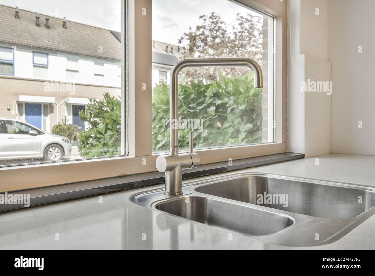 a kitchen sink in front of a window with a view of the street and trees ...