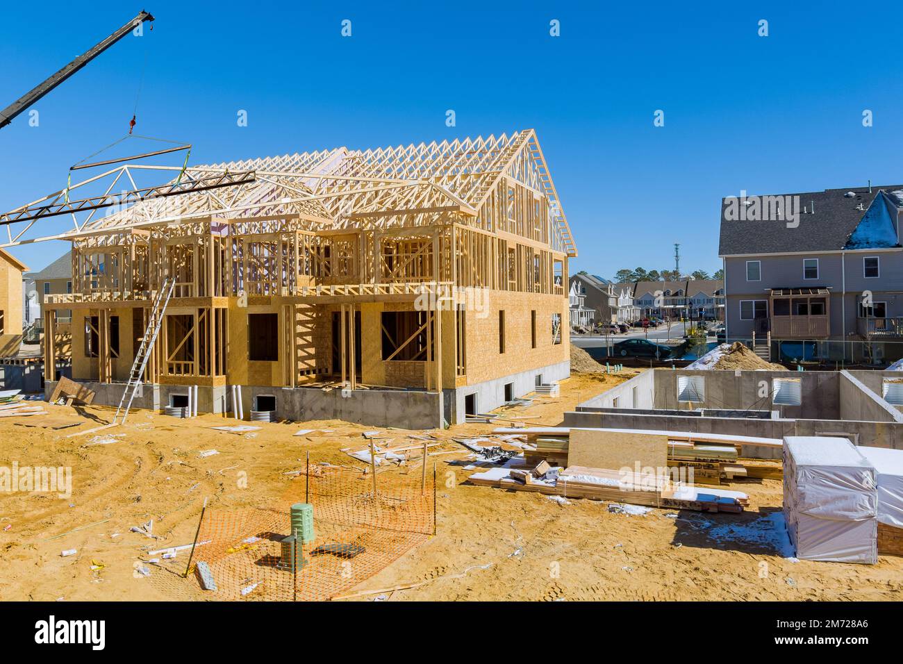 Crane holds wood truss beams as it installs construction framework ...