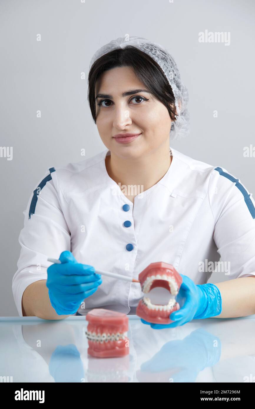 Orthodontist showing model of human jaw with wire braces and aligners ...