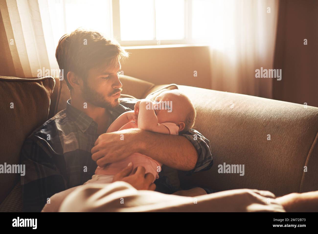 Safe in his arms. a young father and his baby daughter in the living ...