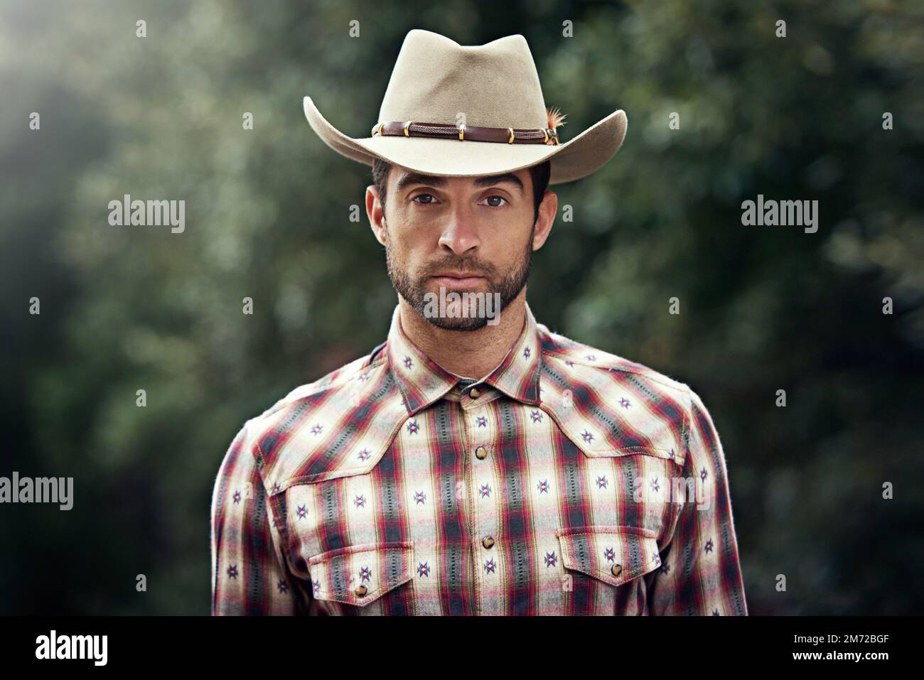 Country couture. a handsome cowboy wearing a check shirt and stetson ...