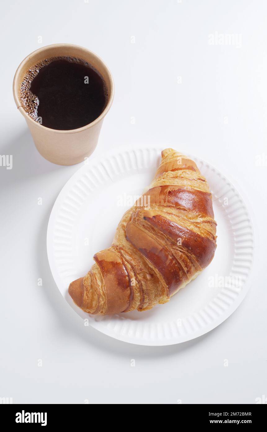 Croissant on paper plate and coffee cup on white background. Takeaway ...