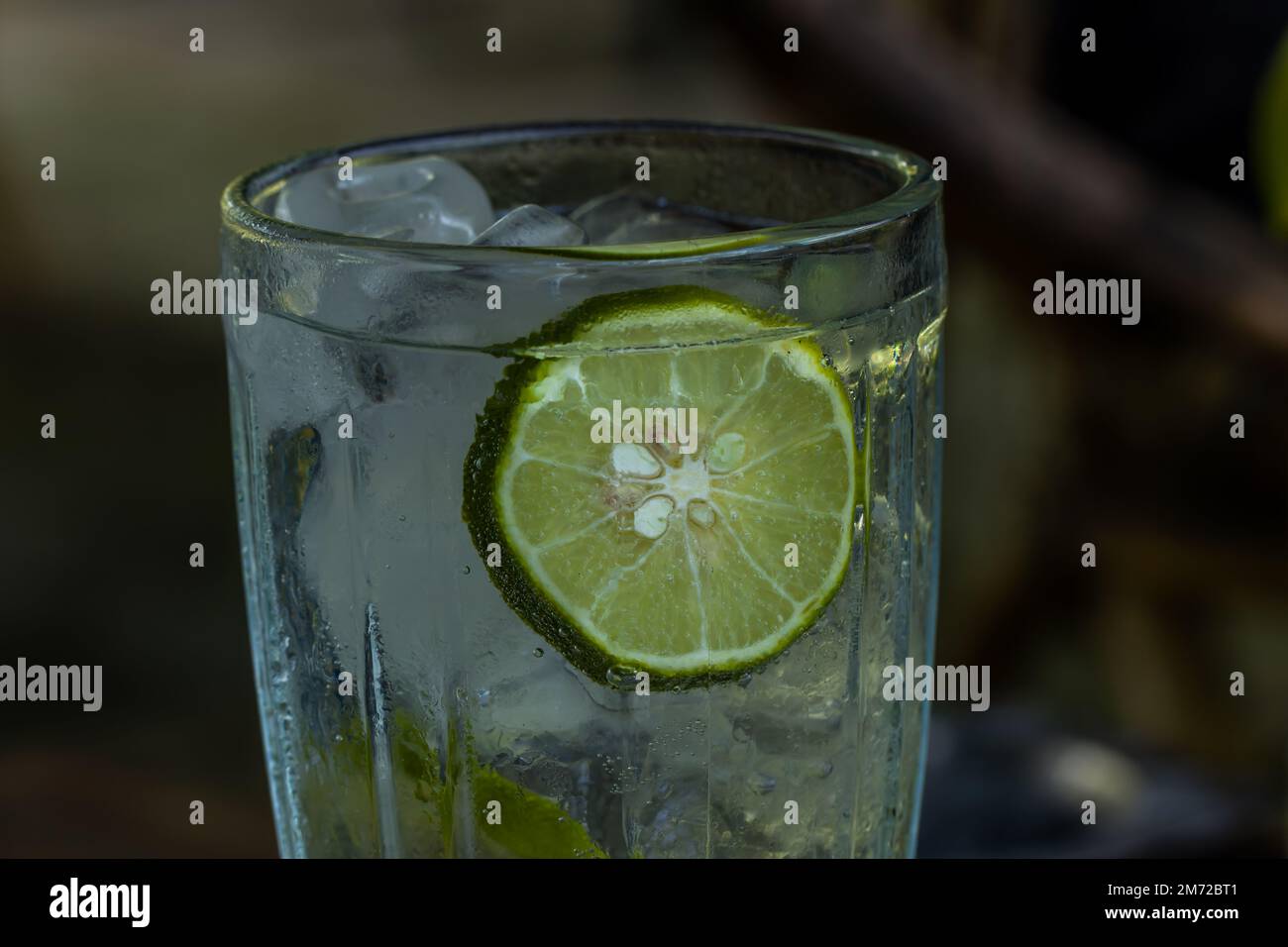 A glass of cold lemon water with ice cubes in a clear glass of glass, a ...