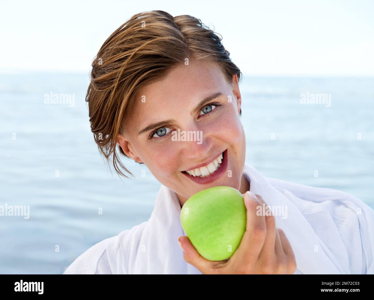 Having a bite at the beach. An attractive young woman taking a bite ...