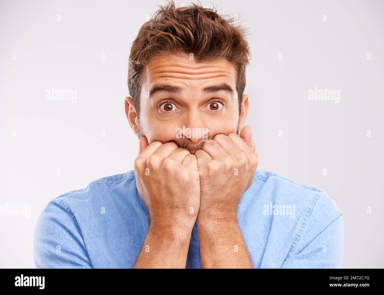 This is nail biting. Studio shot of a handsome young man biting his ...