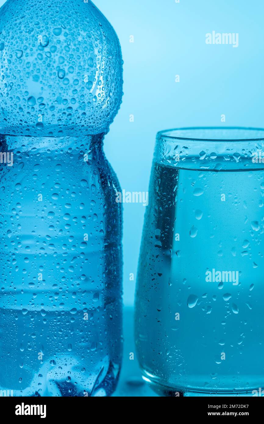 Water pouring from a plastic bottle into a glass beaker on a blue ...