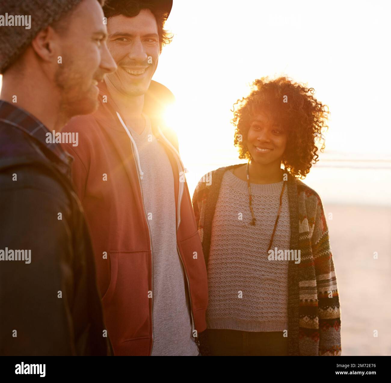 So where we heading. a group of friends walking along a beach at sunset ...