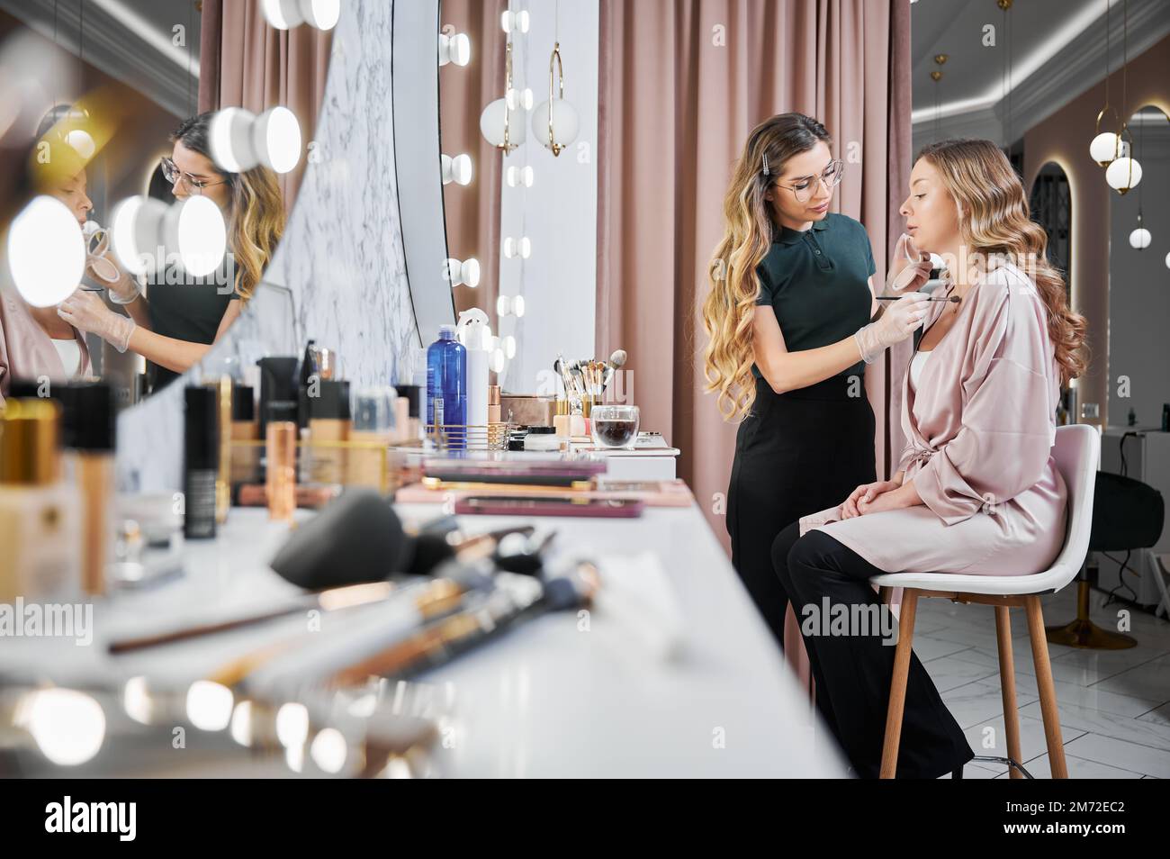 Female beauty specialist applying foundation with cosmetic brush. Young ...