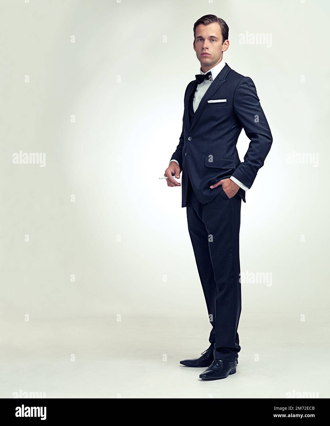 A gentleman and his cigarette. A full length studio portrait of a ...