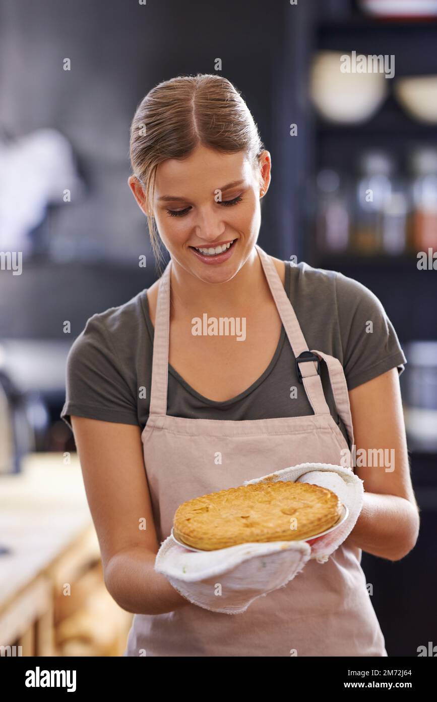 The pie expert. an attractive young woman standing in a kitchen holding ...