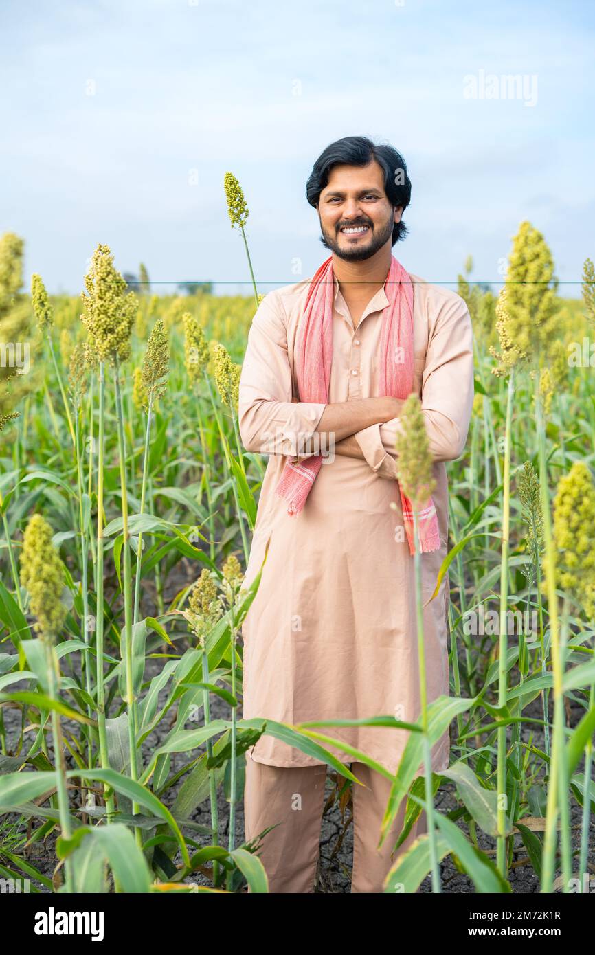 full shot of Confident young indian farmer standing with crossed arms ...