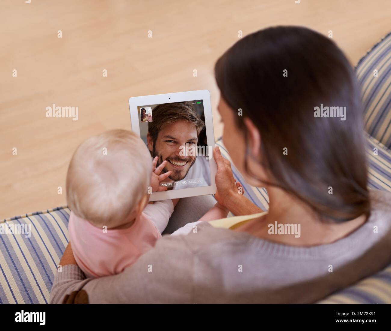 Say hi to Daddy. a happy mother showing her baby daughter a picture of ...