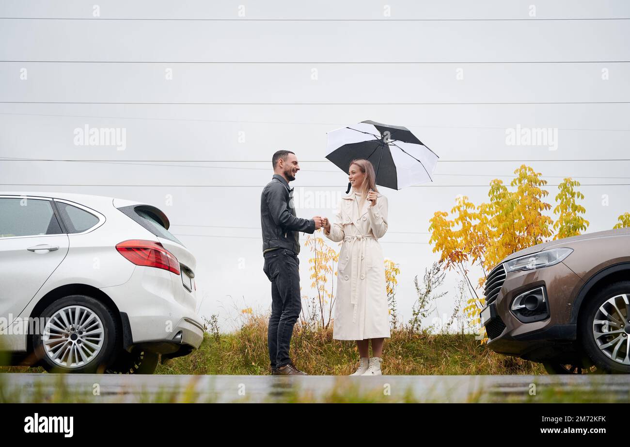 Happy couple in love standing on the road near cars under cloudy sky ...