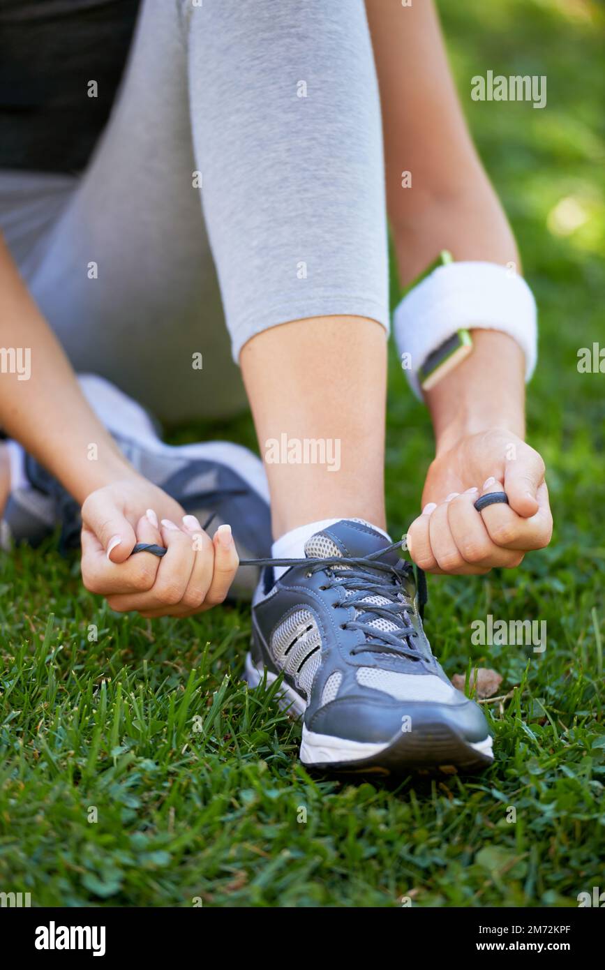 Ready to be tied up in a workout. a runner tying her shoelaces Stock ...