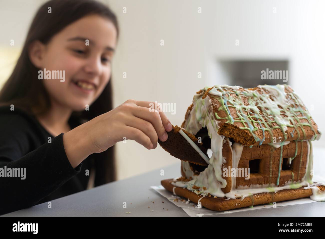 A teenage girl is eating a gingerbread house Stock Photo - Alamy