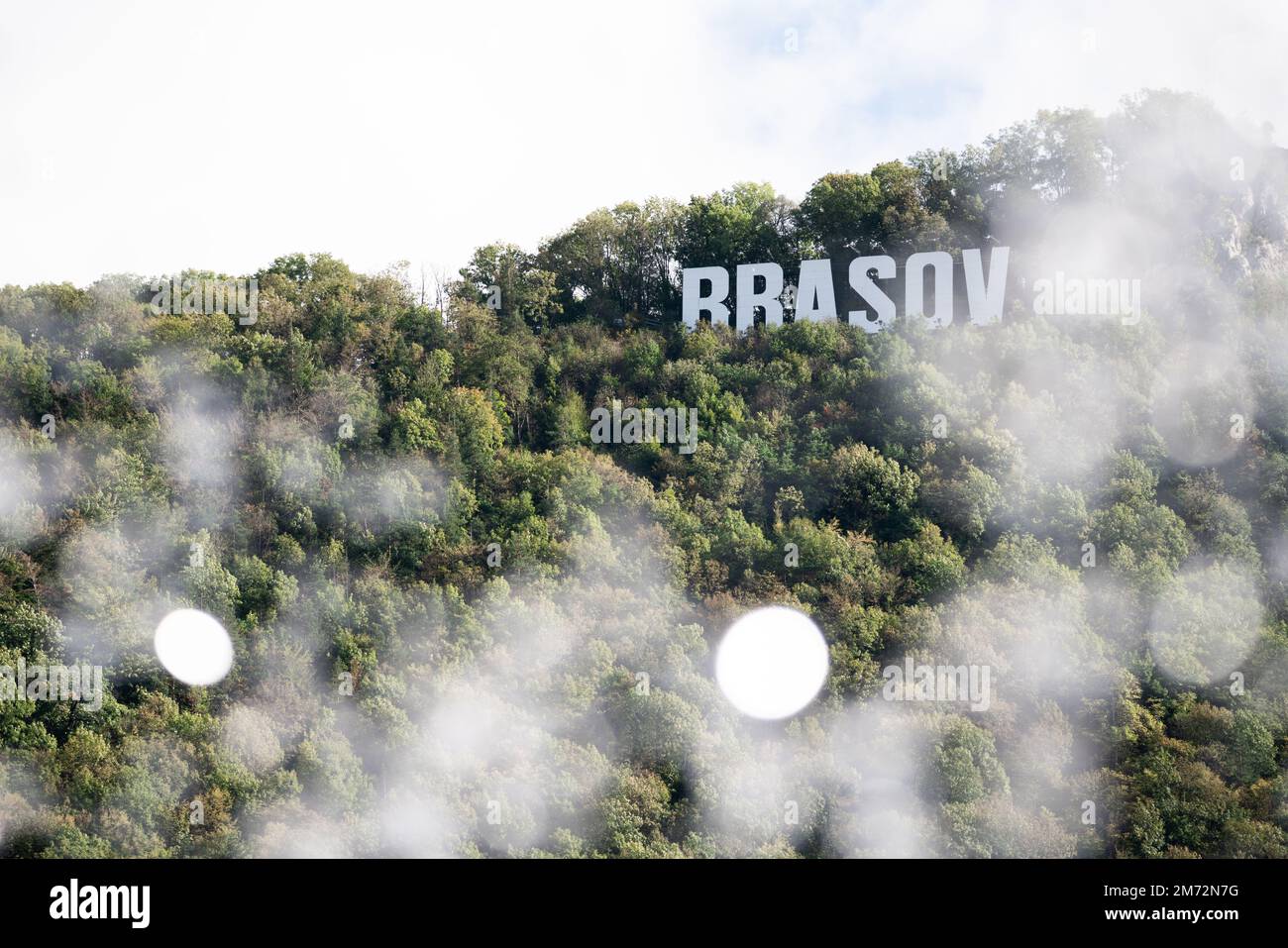 An inscription of Brasov city name on a hill under a blue sky on a ...
