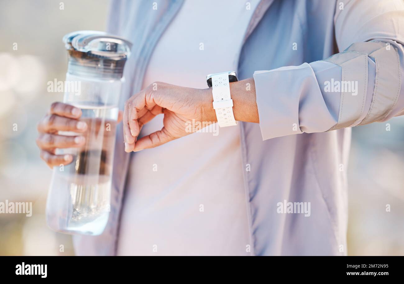 Water bottle, fitness and smartwatch with woman runner outdoor, cardio ...