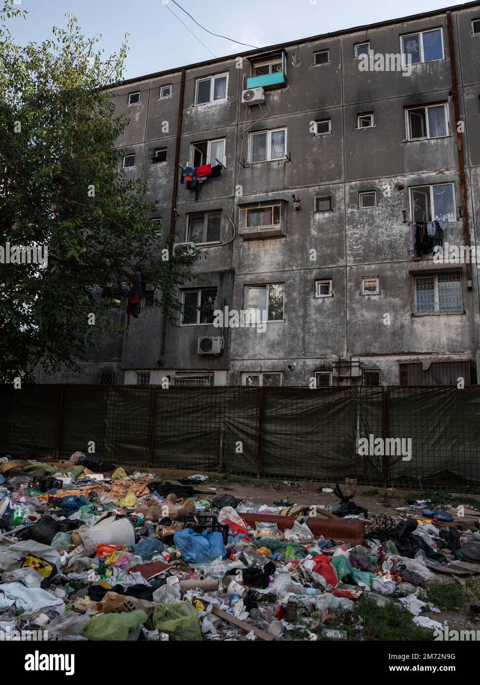 A vertical shot of a pile of garbage in front of old grungy apartment ...