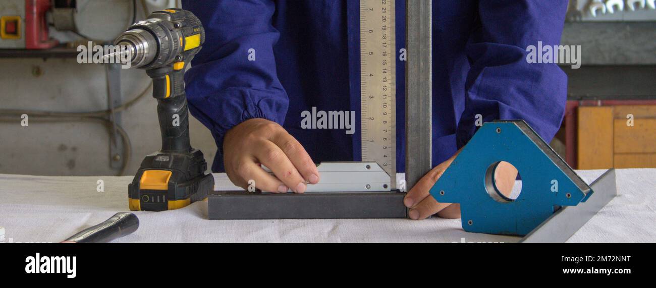metalworker in the workshop who finds the precise angle of a mechanical ...