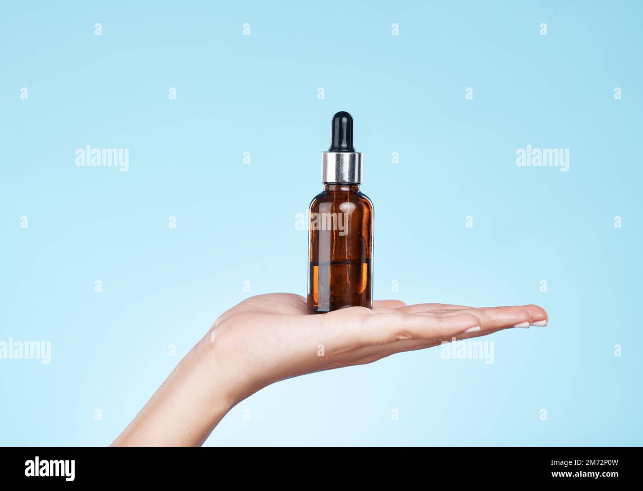 Hand, product and serum with a woman in studio on a blue background to ...