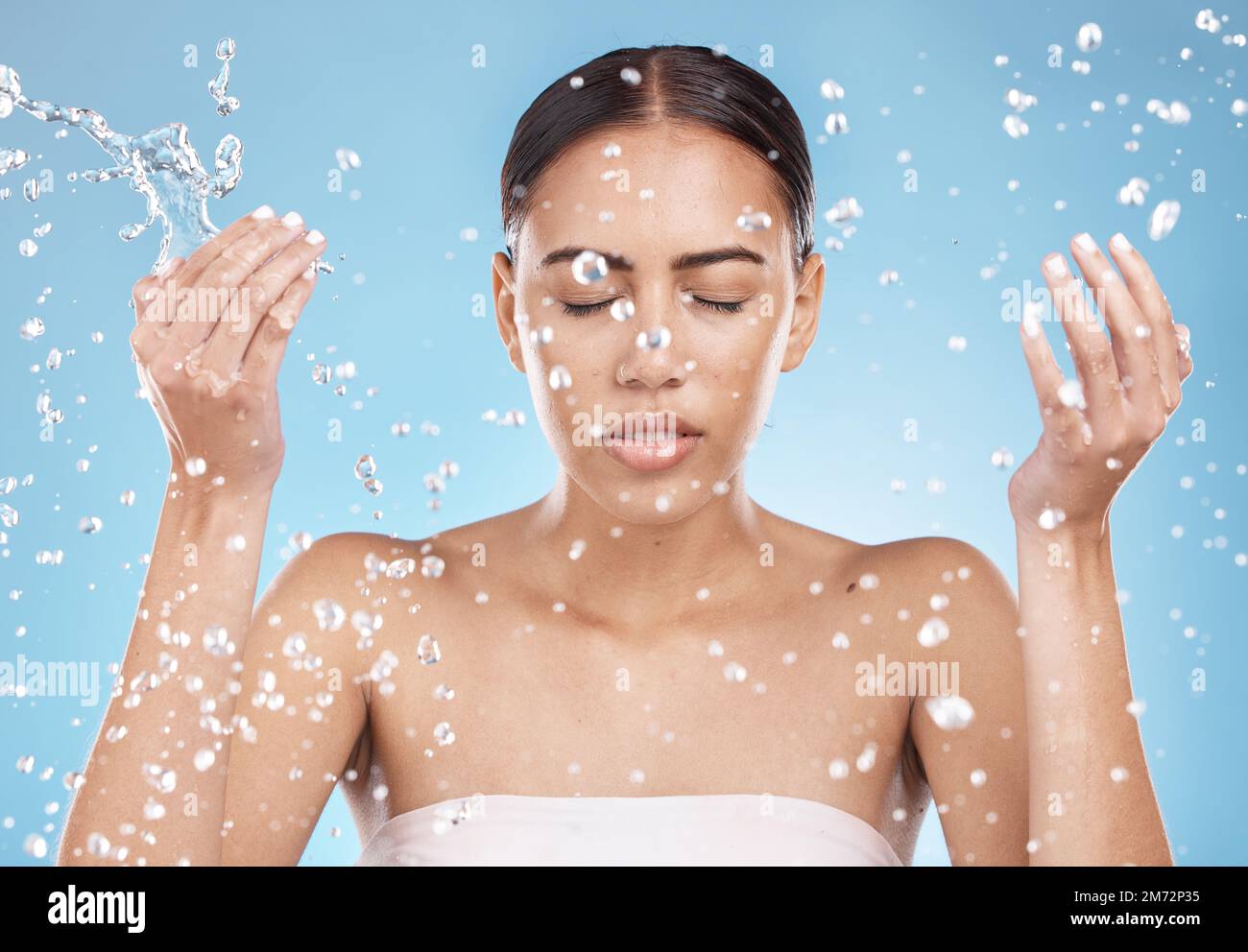 Woman skincare, washing face or water splash on blue background studio for dermatology wellness ...