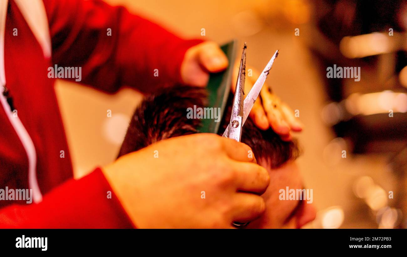 A closeup shot of a Caucasian barber cutting his client's hair Stock ...