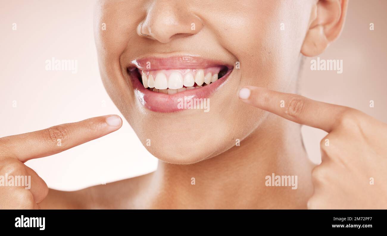 Smile, mouth and woman pointing to teeth on studio background for ...