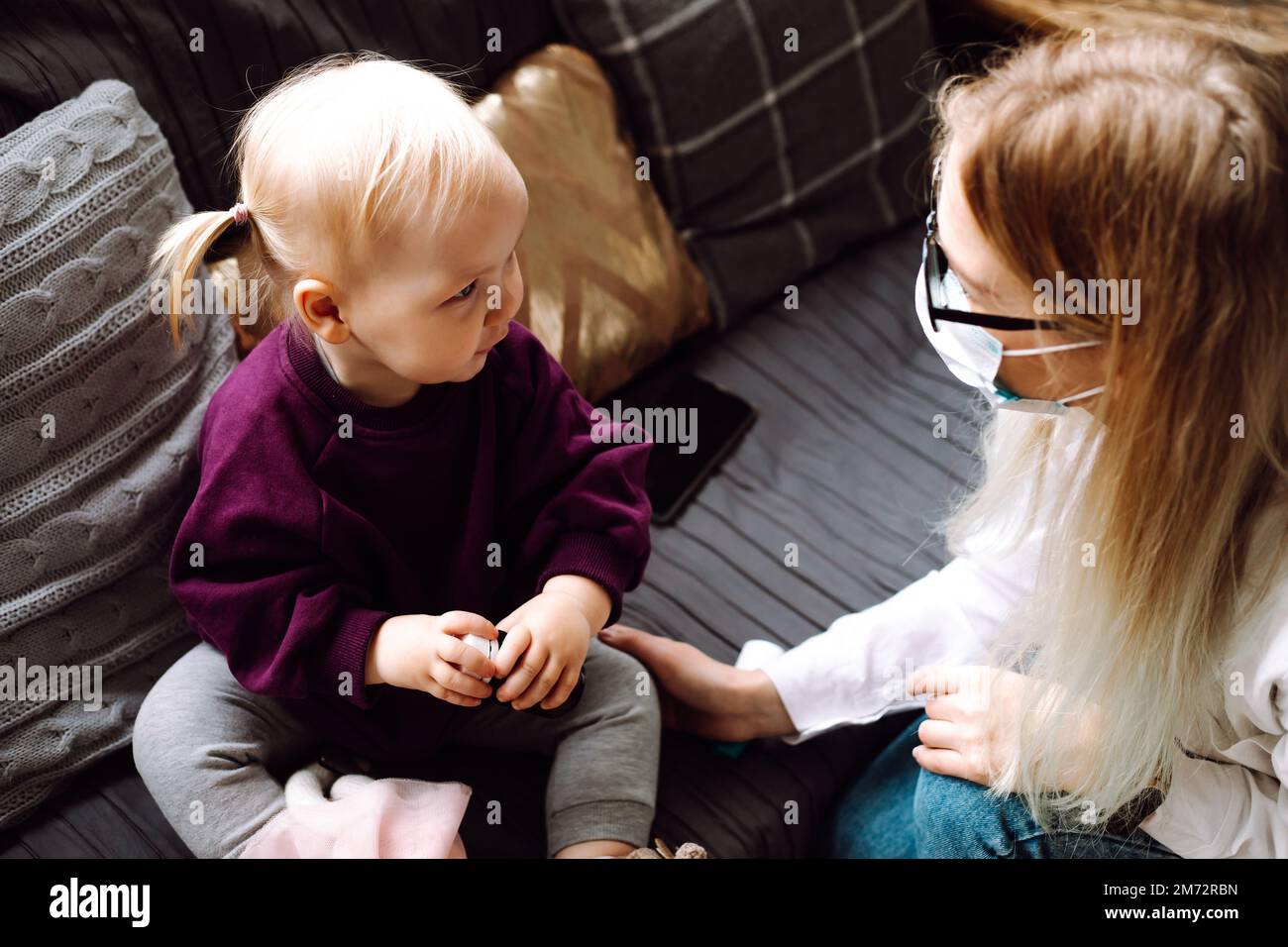 Top view of amazing blond little girl toddler sitting on sofa, looking ...