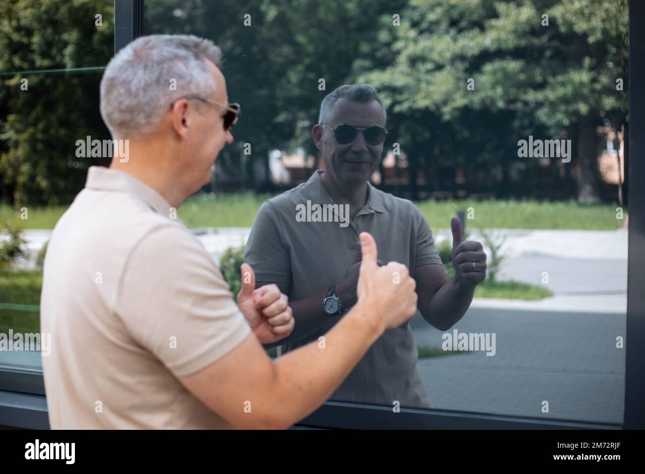 Confident, relaxed mature gray haired man in sunglasses show thumb up ...