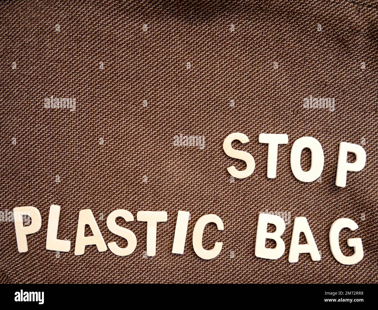 Text "Stop plastic bag" on cotton bag background, on top view with copy ...