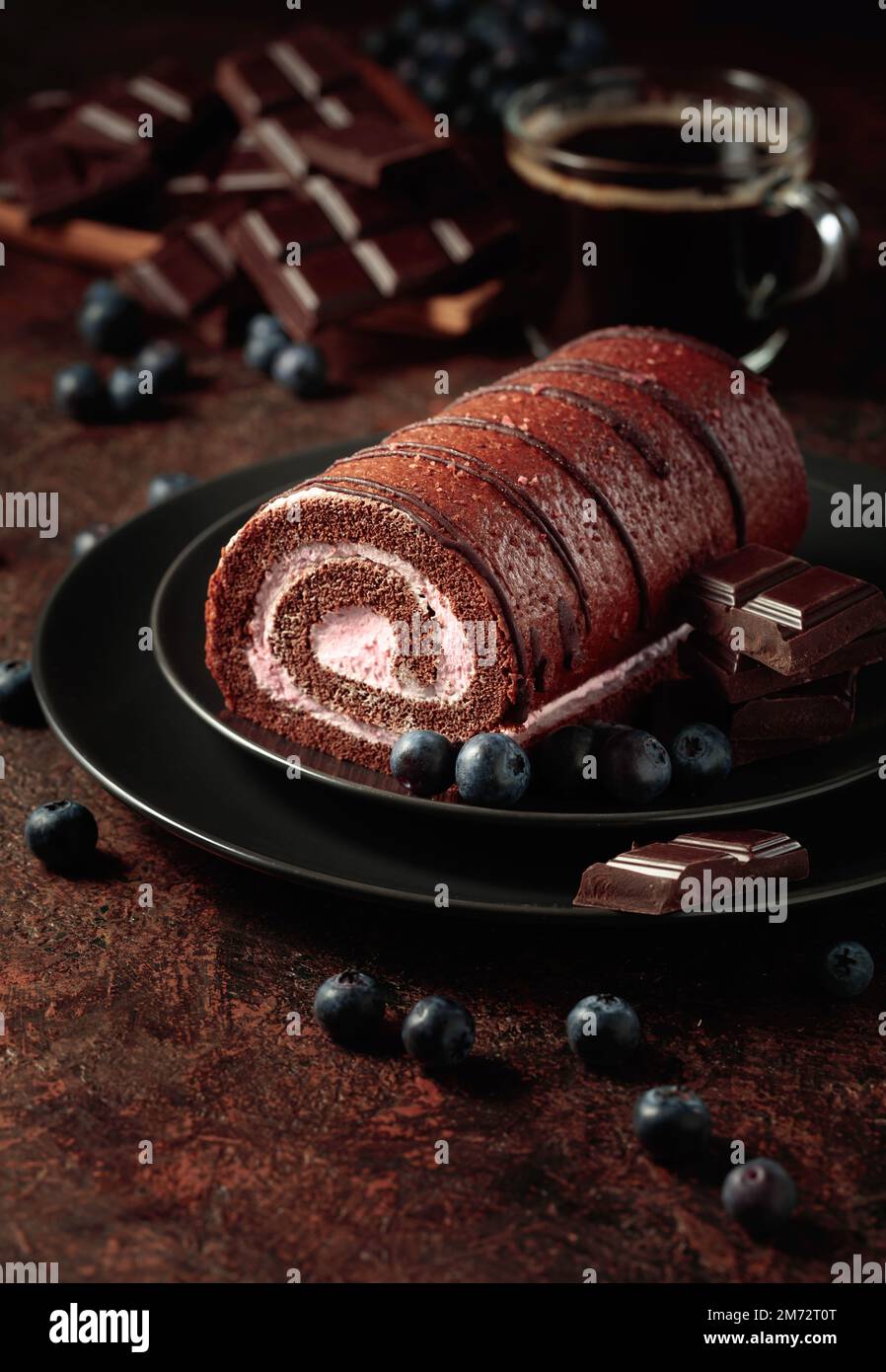 Chocolate roll cake with blueberries and a broken black chocolate bar ...