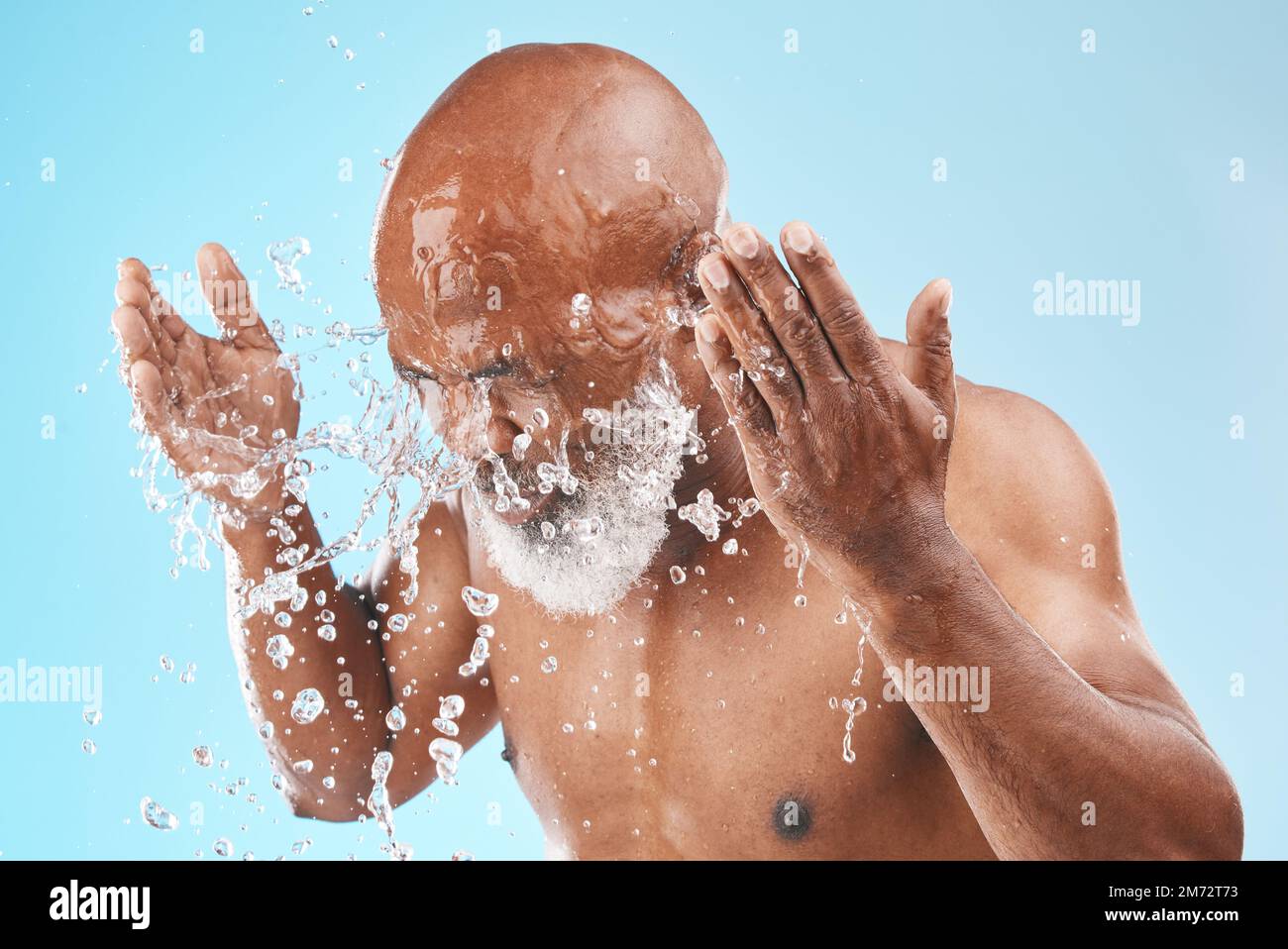 Black man cleaning face with water splash, healthy skincare on studio blue background for shower ...