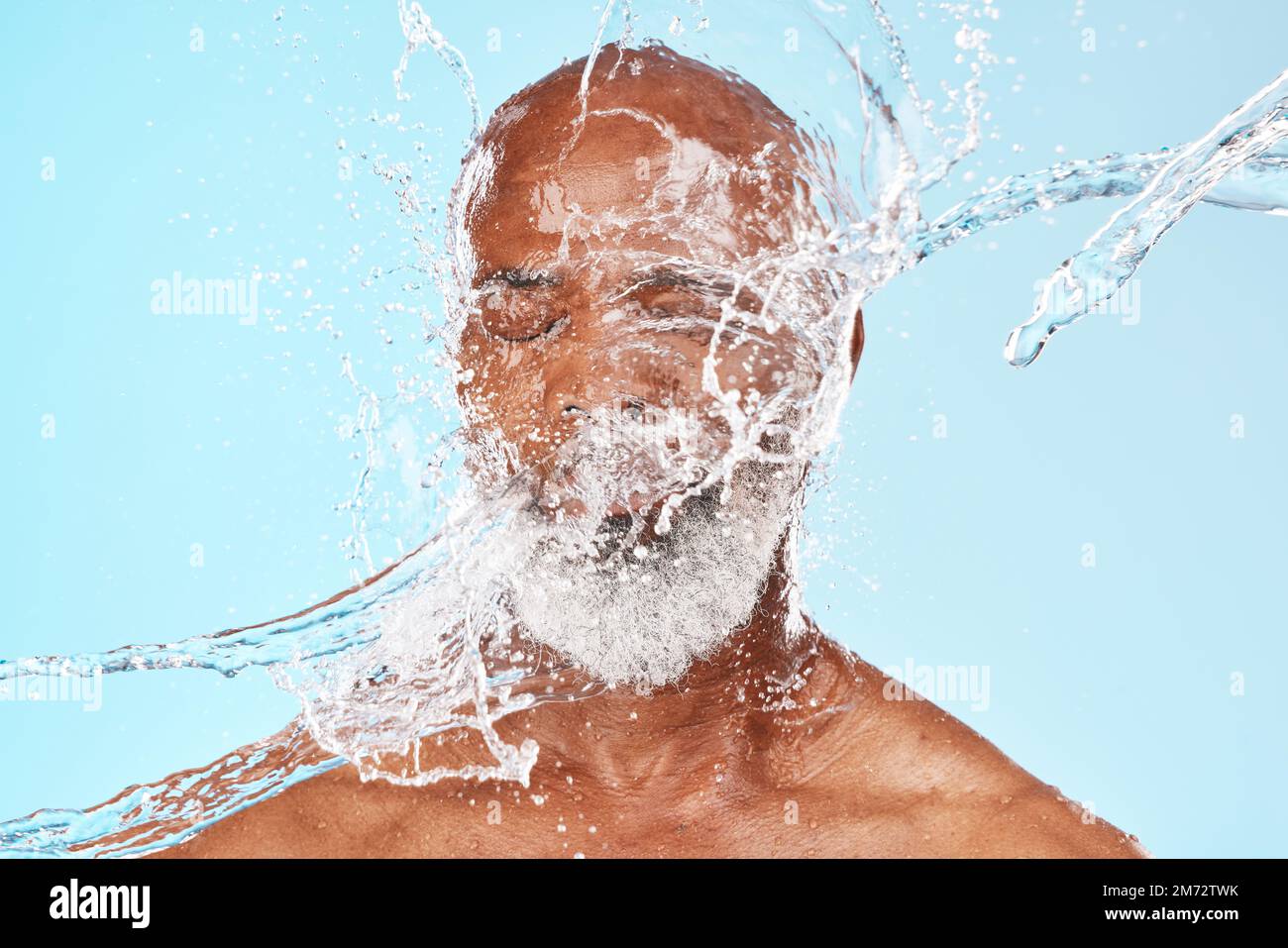 Elderly black man, water splash and face in studio for wellness, clean or facial health by ...