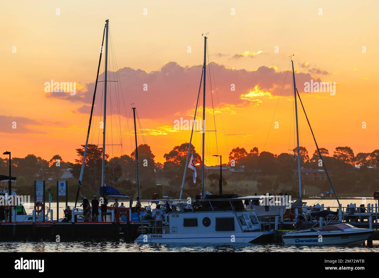Sailboats moored at pier against a setting sun, Gippsland Lakes ...