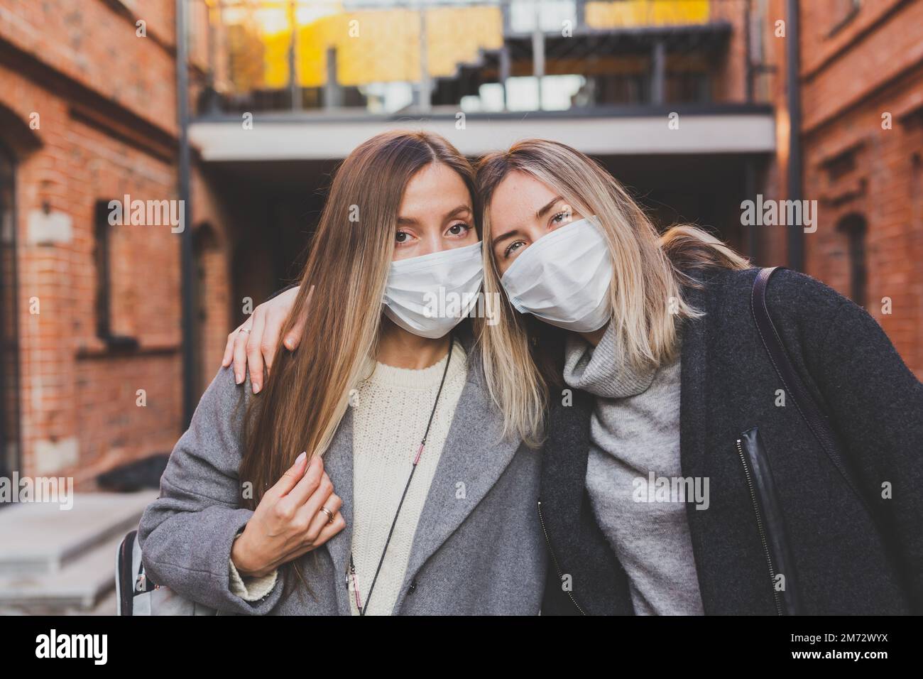 Young pretty girls friends in medical masks having fun outdoor in ...