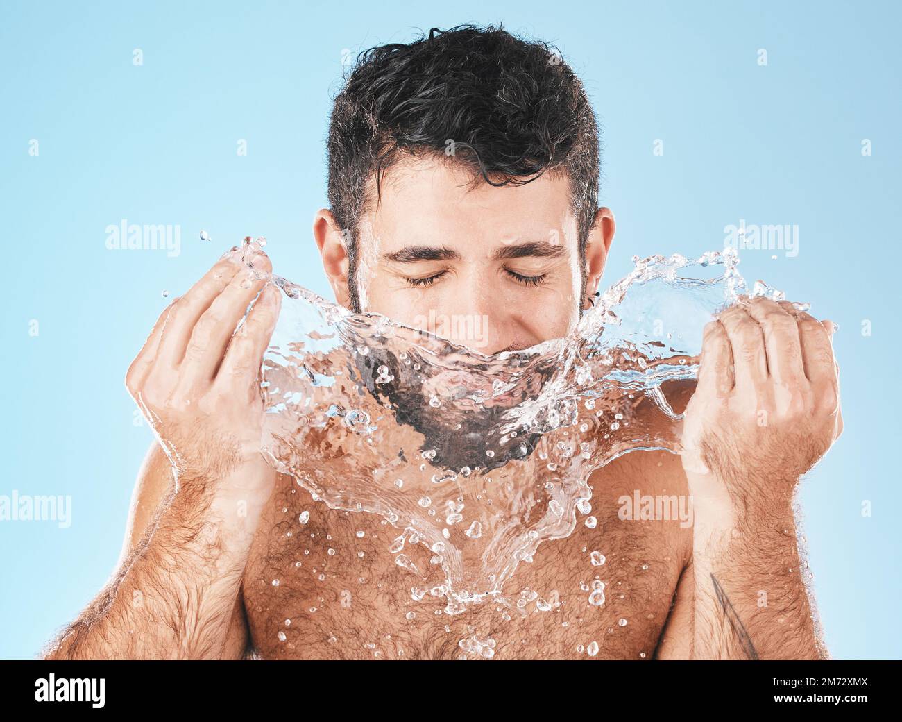 Man, splash and face for beauty in studio for wellness, health or self care cleaning by blue ...