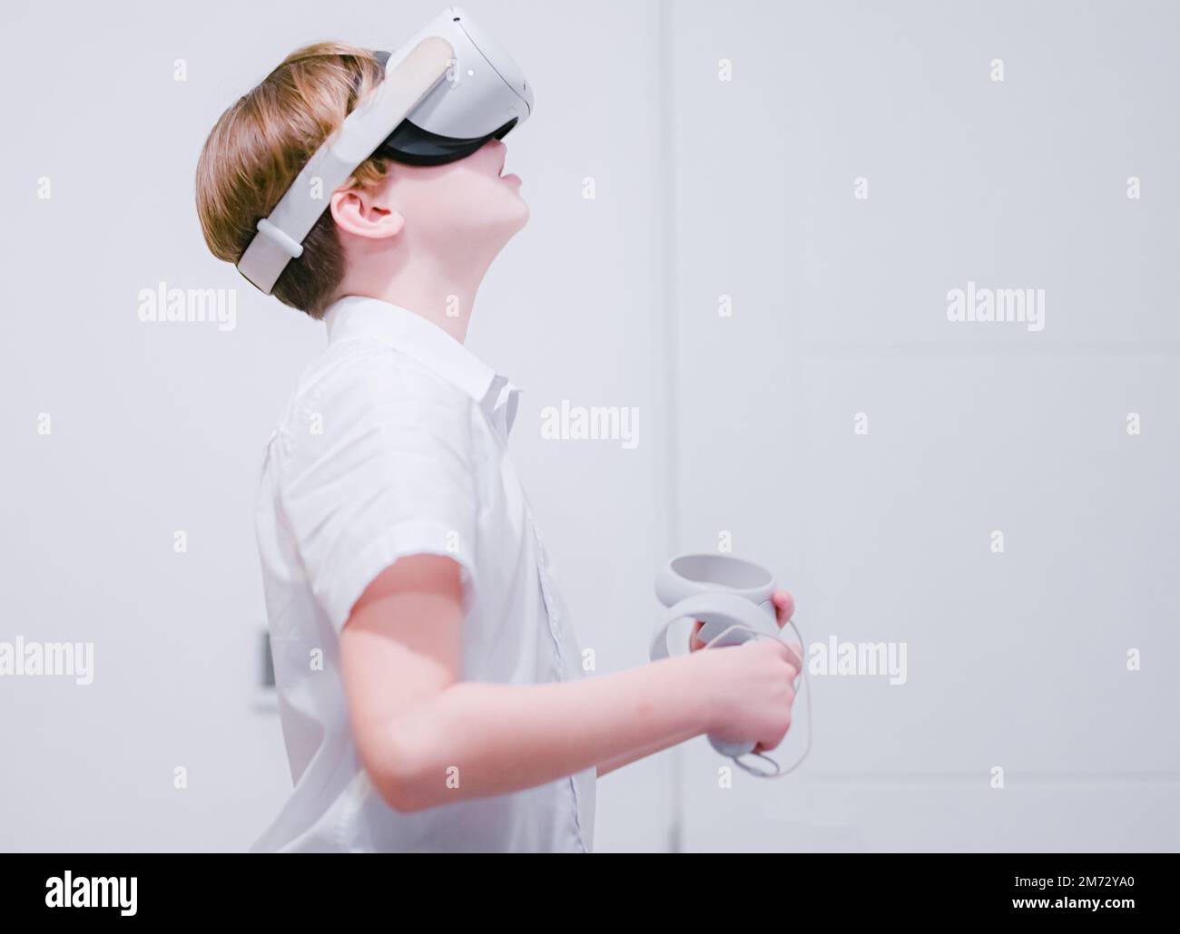 Young teenage boy wearing virtual reality head set in clean white ...