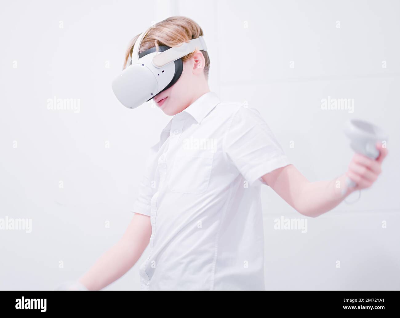 Young teenage boy wearing virtual reality head set in clean white ...
