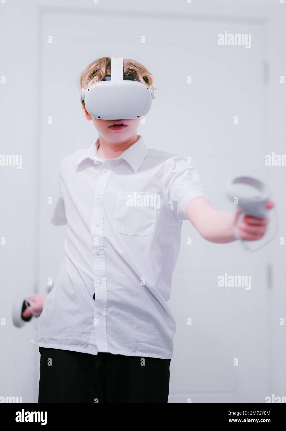Young teenage boy wearing virtual reality head set in clean white ...