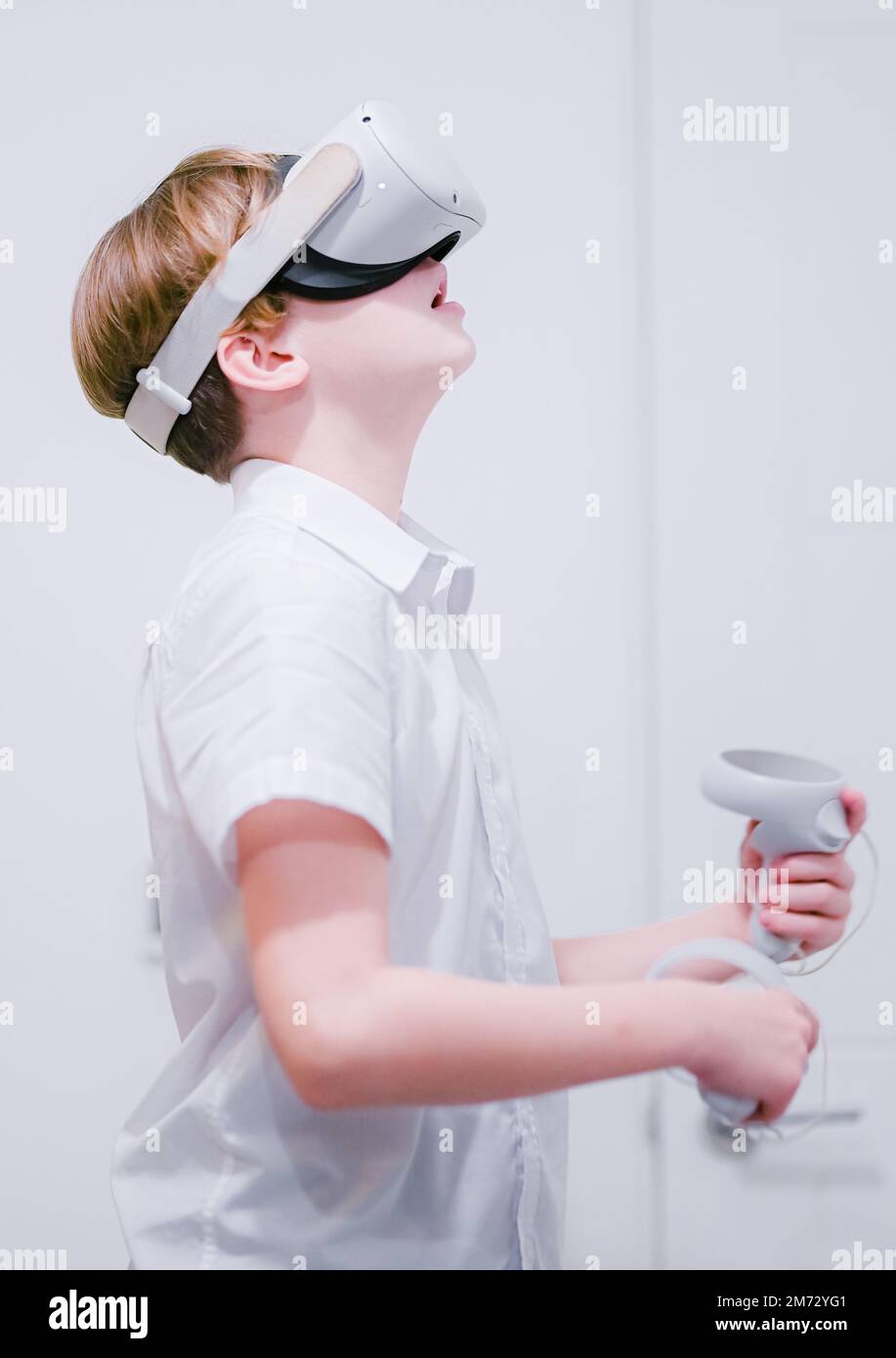 Young teenage boy wearing virtual reality head set in clean white ...