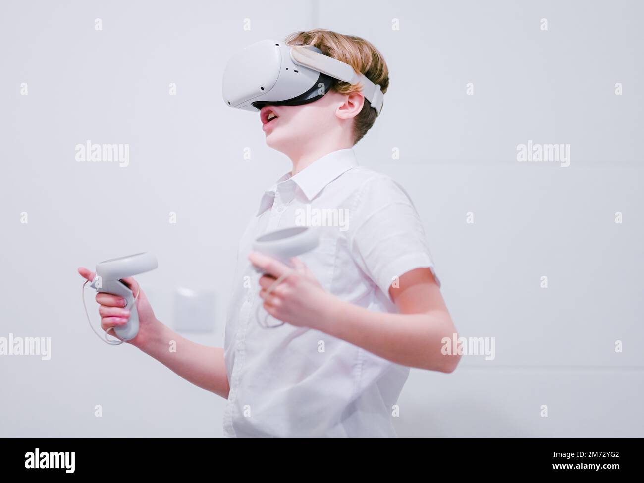 Young teenage boy wearing virtual reality head set in clean white ...
