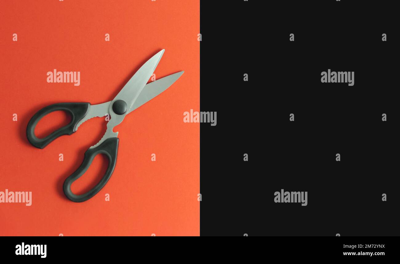 Open scissors on red and black paper background Stock Photo - Alamy