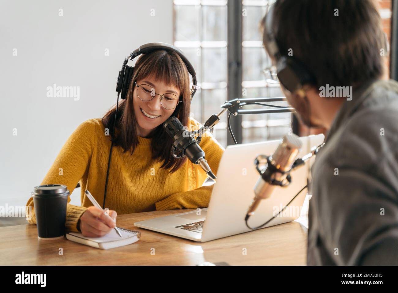 Female podcaster in headphones interviewing man guest using microphone ...