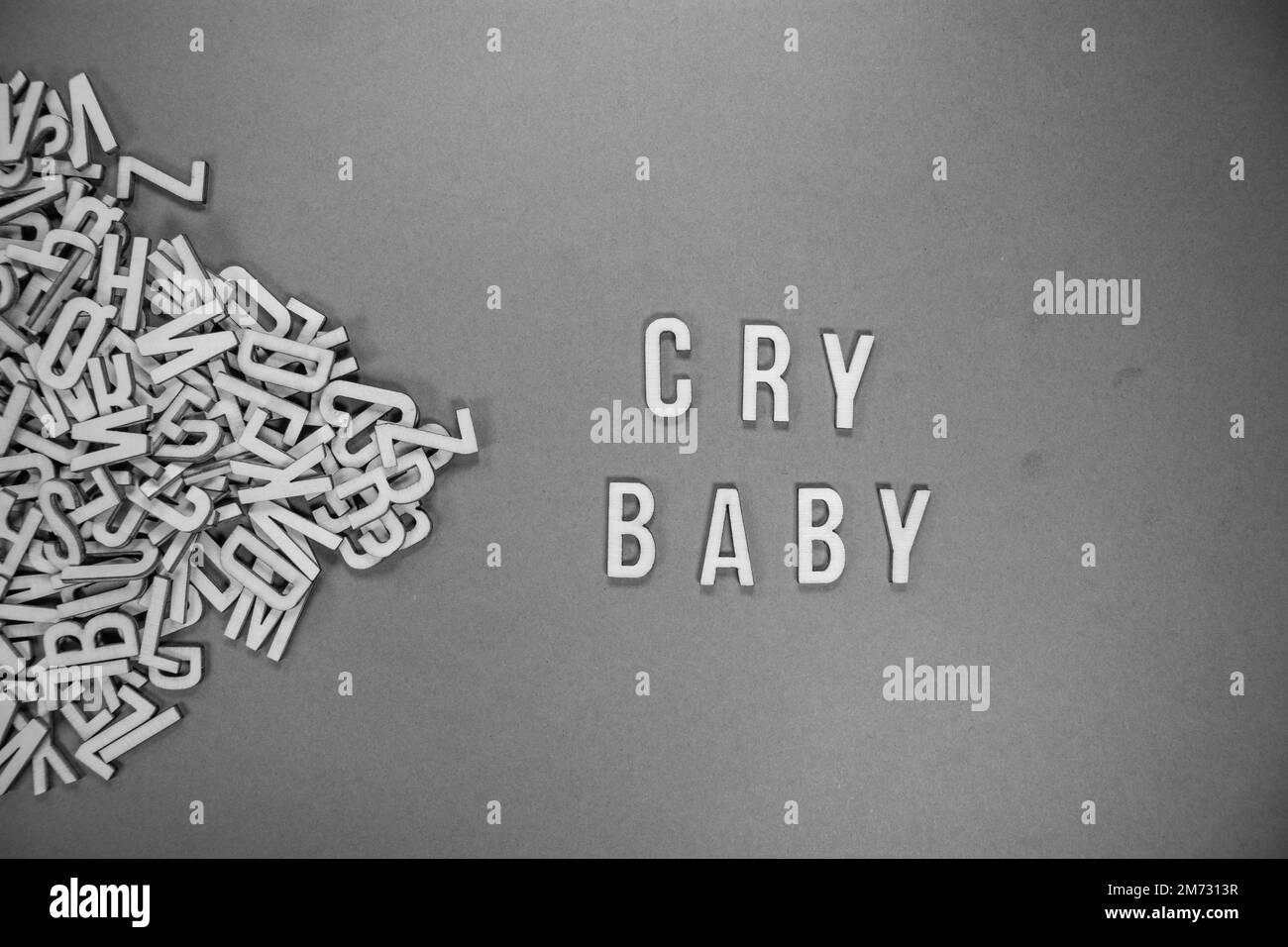 CRY BABY in wooden English language capital letters spilling from a ...