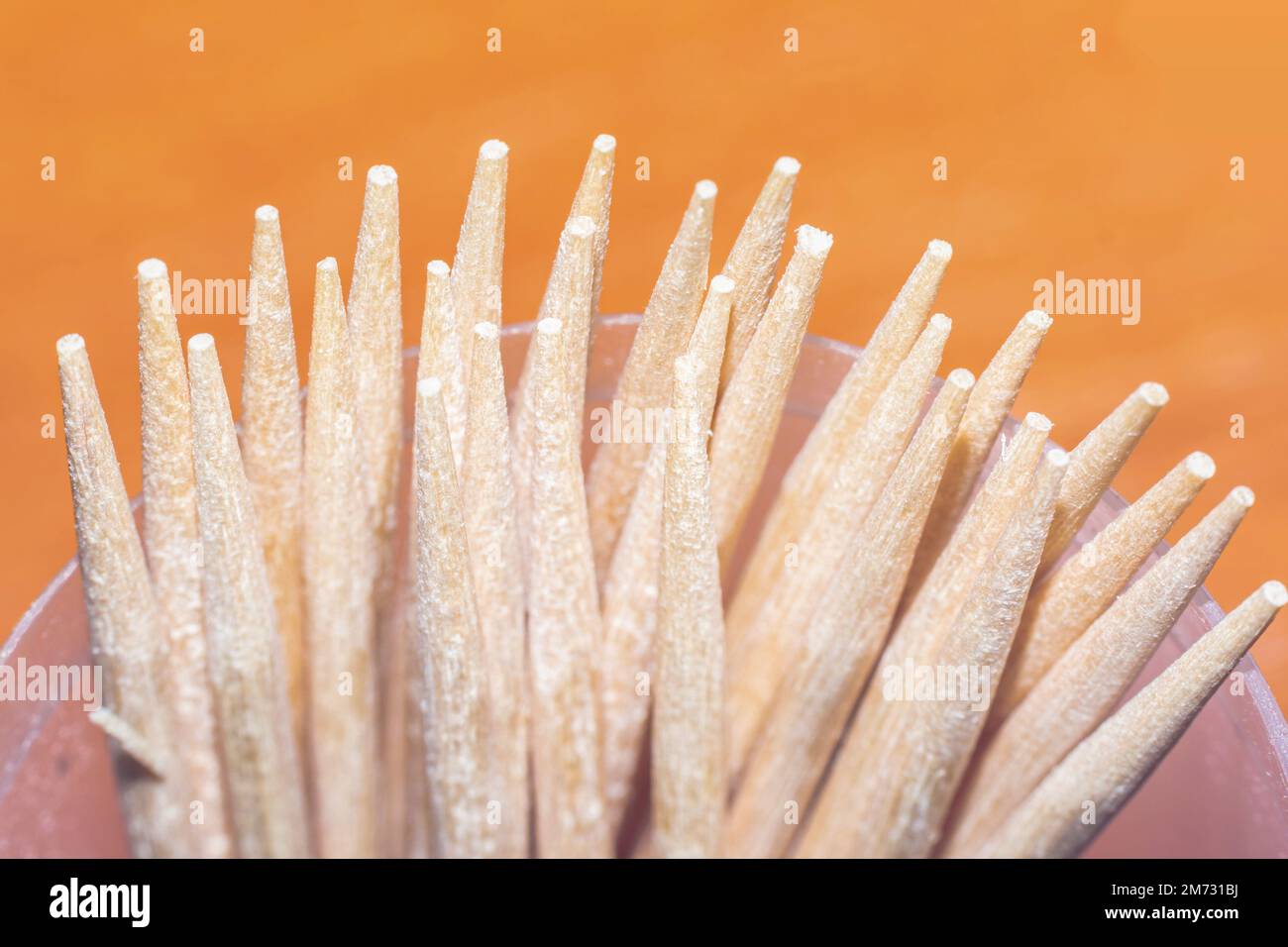Many toothpicks next to each other in a close-up, orange background ...