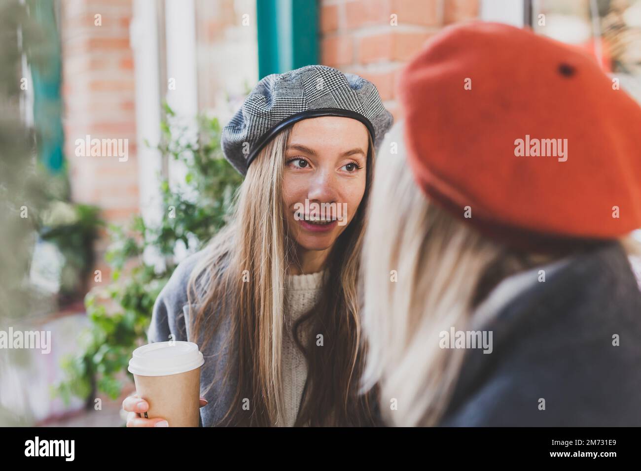 Young female best friends talking to each other discussing interesting themes during free time ...