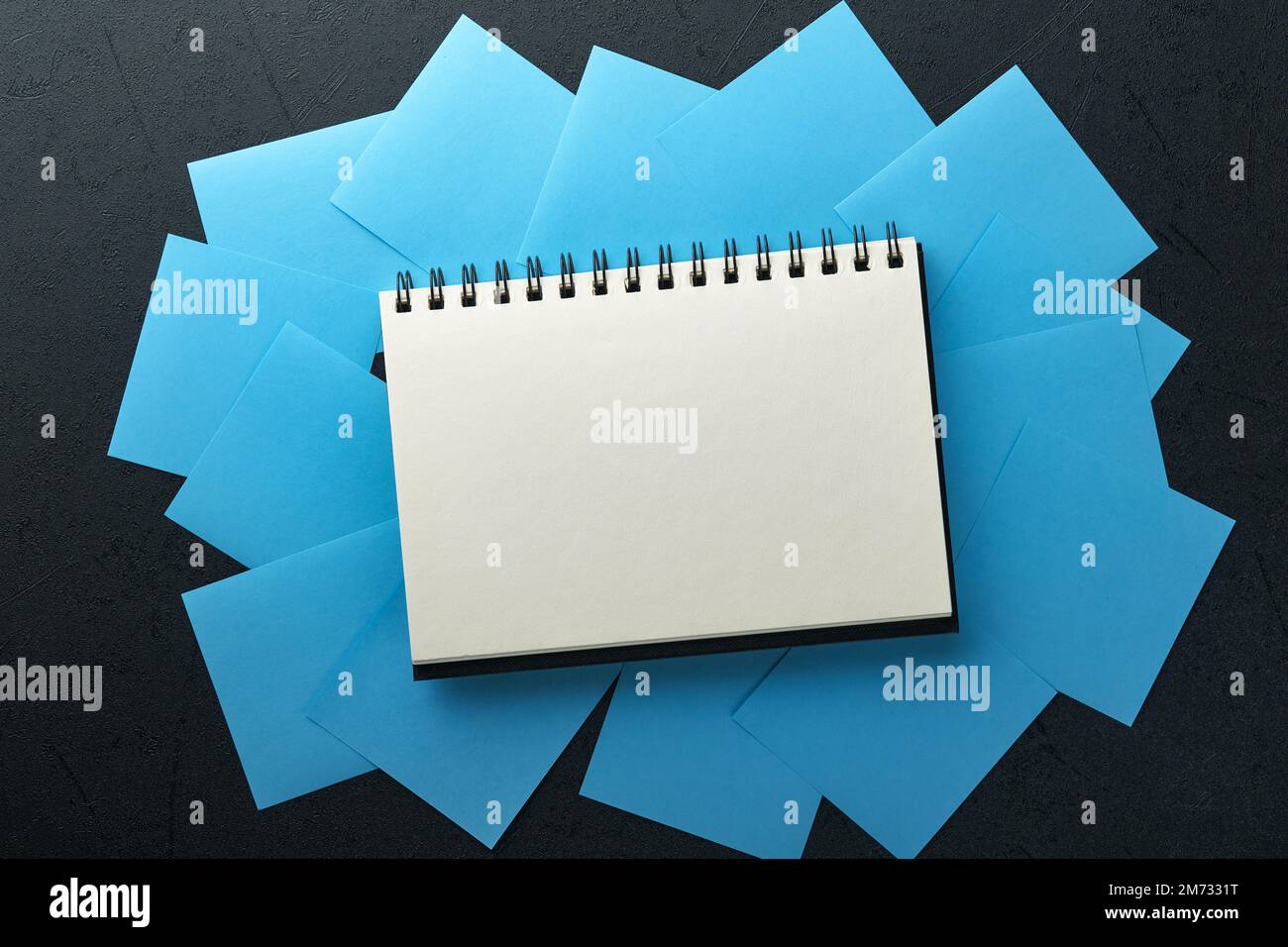 Blue paper stickers and notepad or book in middle on black background ...