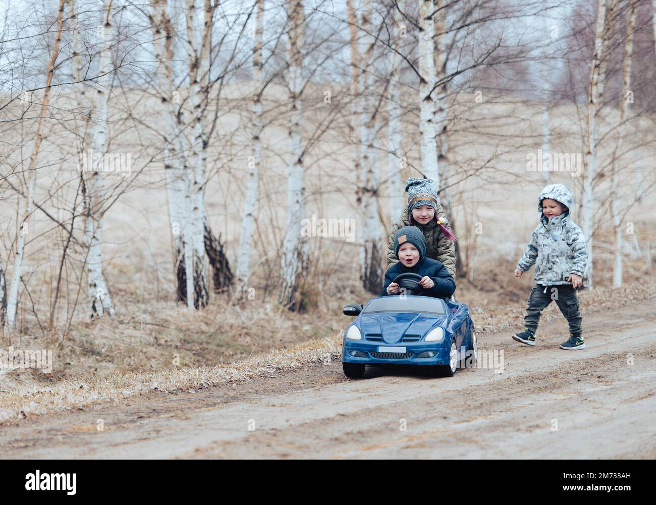Three happy kids having fun drive a blue toy car, road trip adventure ...