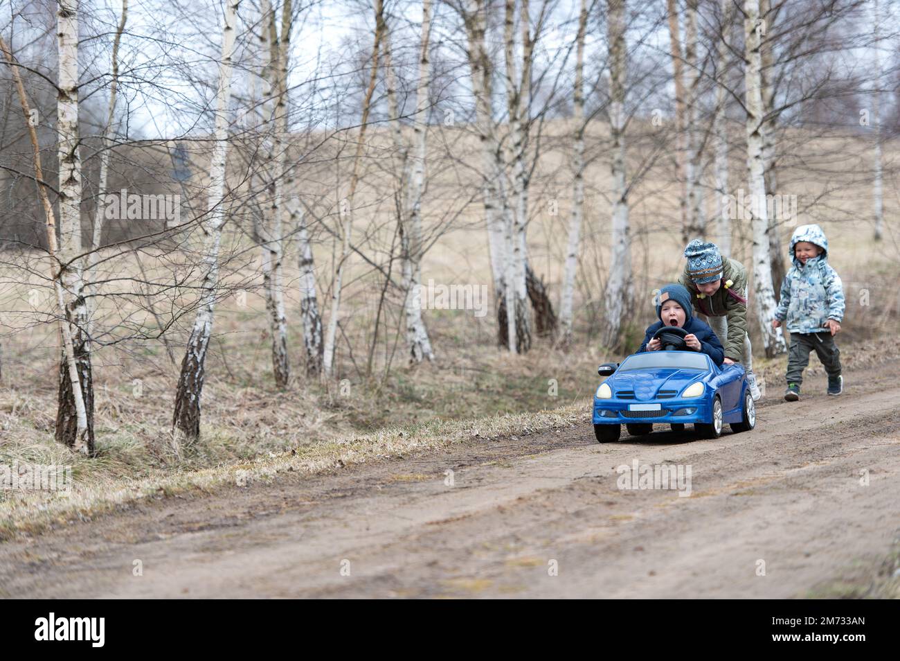 Three happy kids having fun drive a blue toy car, road trip adventure ...