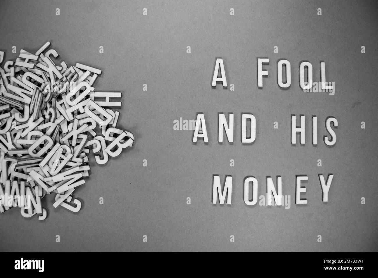 A FOOL AND HIS MONEY in wooden English language capital letters ...
